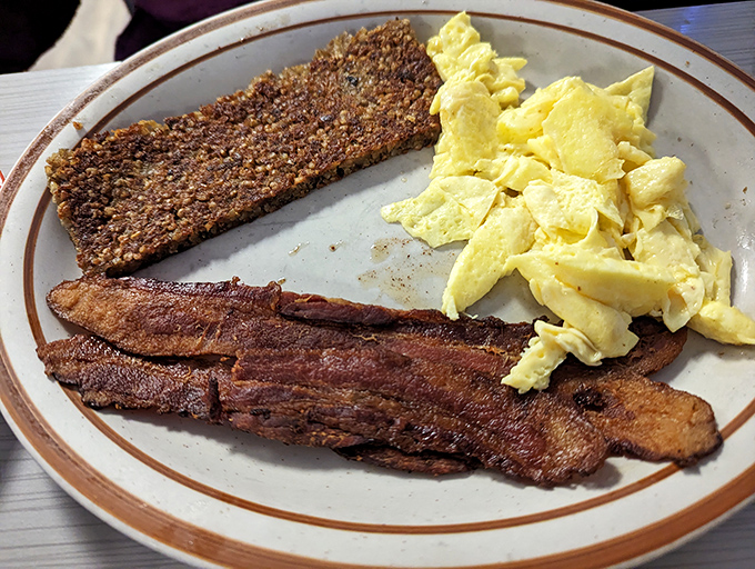 Breakfast's holy trinity: crispy bacon, farm-fresh scrambled eggs, and goetta&mdash;Kentucky's gift to the breakfast world. Simple perfection on a plate.