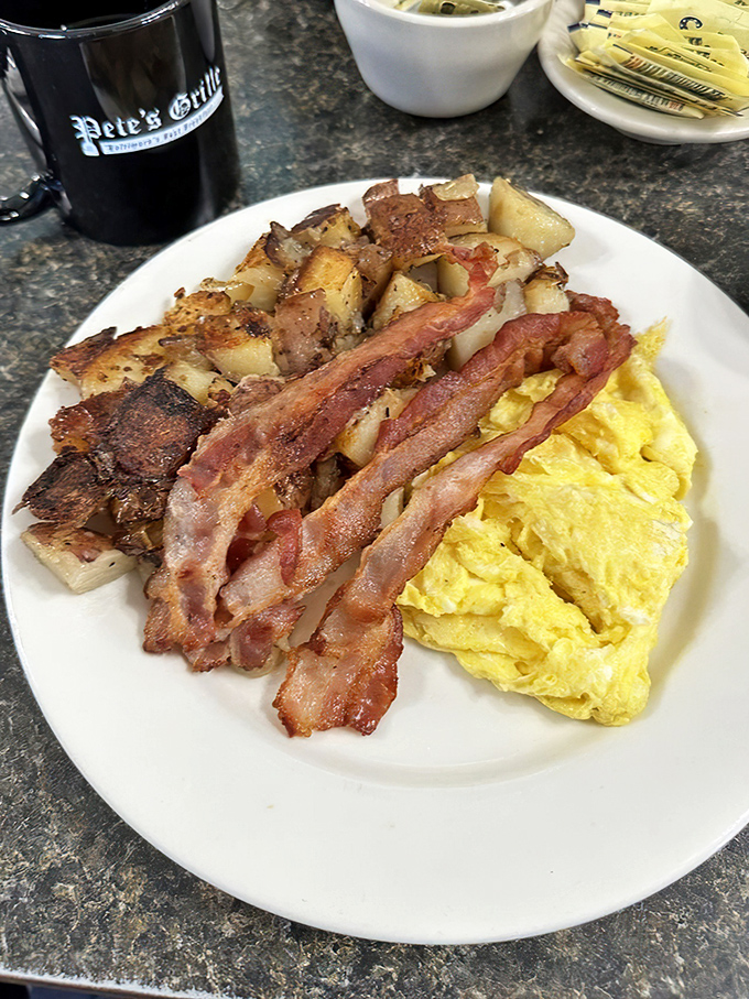 Breakfast perfection on a plate: sunshine-yellow eggs, home fries with perfectly crisped edges, and bacon that's achieved that magical crisp-yet-chewy state.