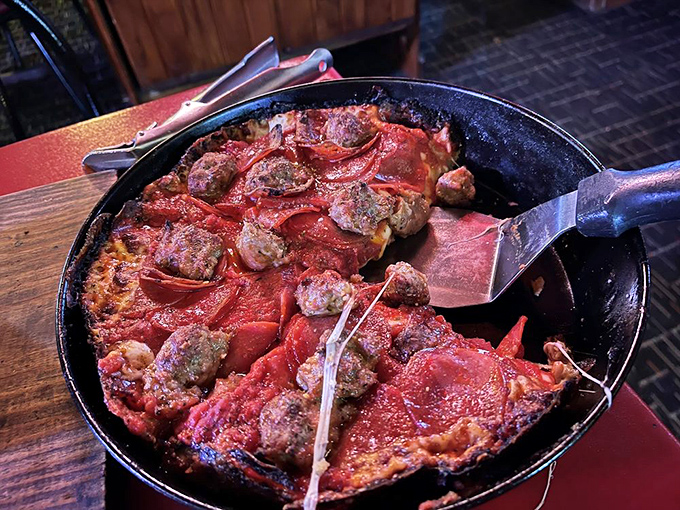 The spatula reveals the masterpiece beneath&mdash;a sausage and pepperoni deep dish with that coveted caramelized cheese edge. Pizza dreams are made of this.