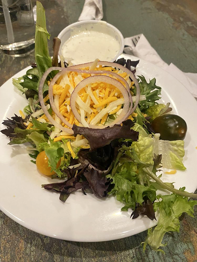 A garden party on a plate. Fresh mixed greens topped with shredded cheese and rings of red onion, proving British cuisine isn't all about heavy comfort foods.
