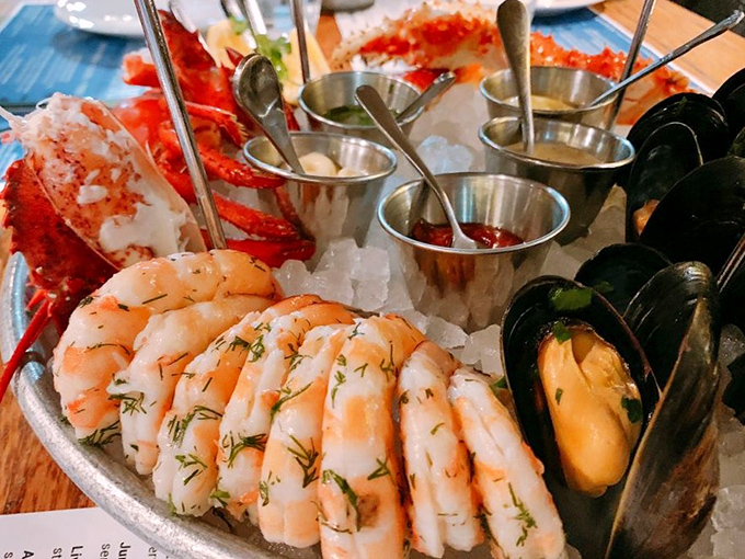 The raw bar spread showcases ocean treasures that would make Neptune himself weep with pure joy.