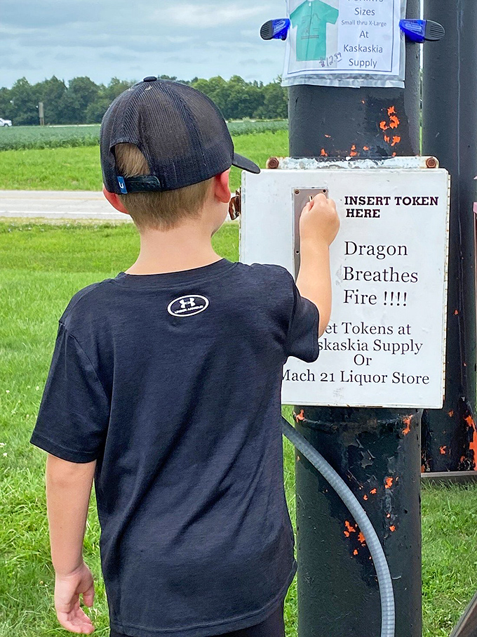 The moment of truth: a young visitor prepares to awaken the sleeping beast, token in hand and anticipation written across his posture.