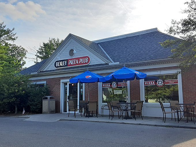 Bexley Pizza Plus hides award-winning pizza magic behind a humble brick facade and blue patio umbrellas.