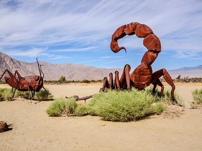 A massive metal scorpion rises from the desert sand, its stinger poised against the backdrop of distant mountains.