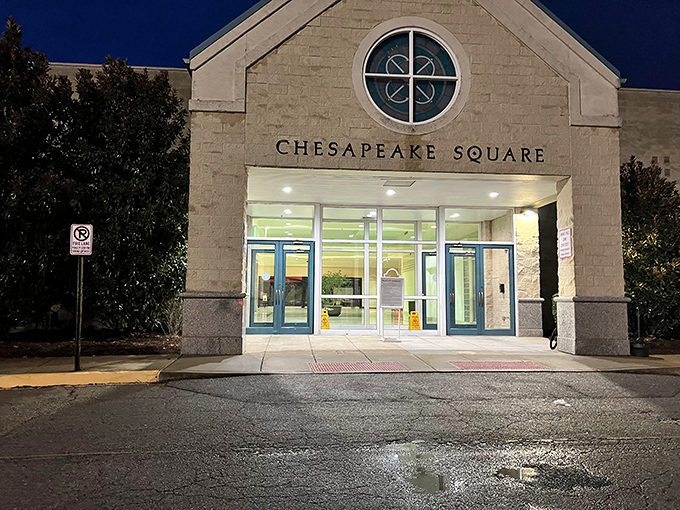 The nighttime entrance to Chesapeake Square glows with welcome. Those glass doors promise climate-controlled bargain hunting regardless of Virginia's weather whims.