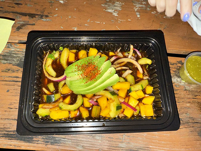 A symphony of colors and flavors. This aguachile's perfectly sliced mango and cucumber dance in citrus marinade, crowned with creamy avocado.