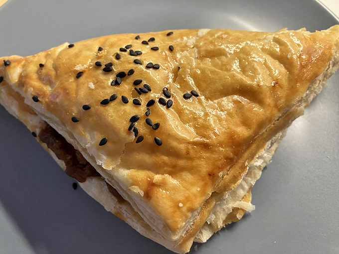 A savory triangle that delivers more flavor per square inch than should be legally possible, topped with sesame seeds for that perfect crunch.