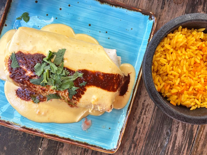 Cheese pull dreams come true! This bean burrito smothered in queso sauce alongside golden rice is comfort food that hugs you from the inside.