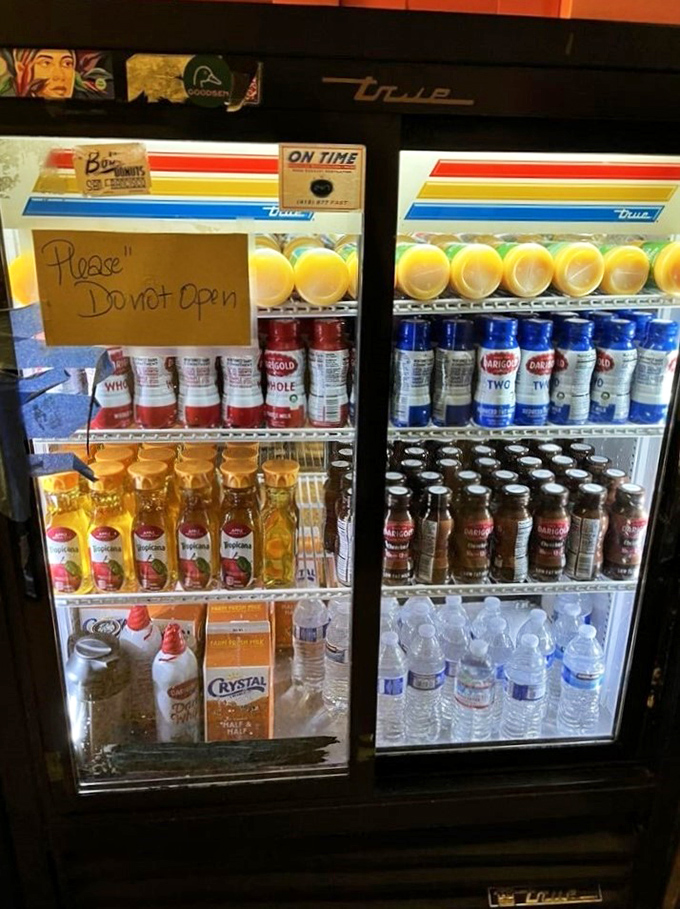The beverage cooler: where liquid companions for your donut await. Notice the polite "Please Do Not Open" sign everyone ignores.