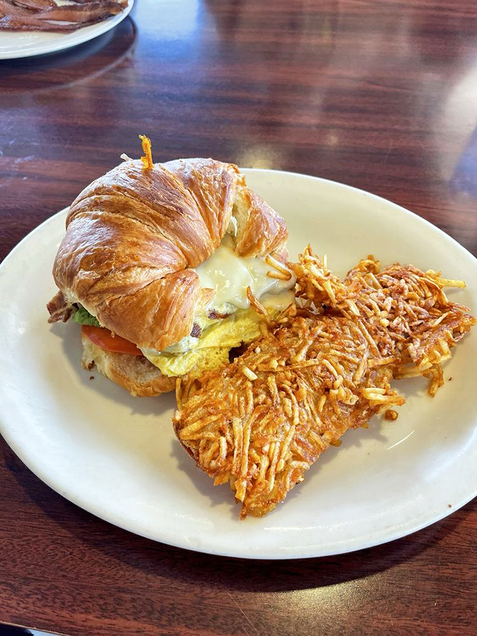 Breakfast architecture at its finest! A golden croissant sandwich with crispy hashbrowns that would make a French baker nod in approval.