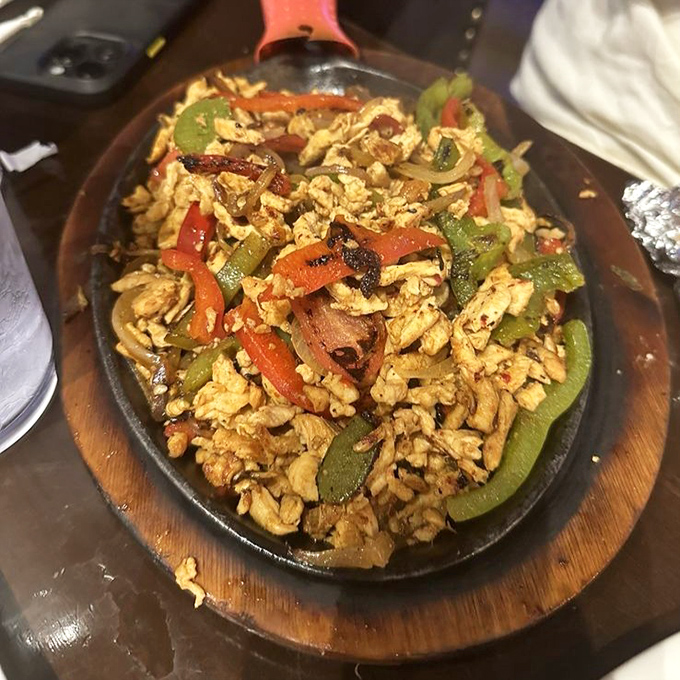 Sizzling chicken fajitas on a wooden platter&mdash;the culinary equivalent of making an entrance with smoke machines and dramatic lighting.