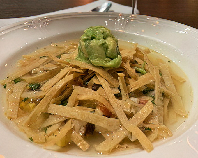 Chicken tortilla soup arrives as a colorful symphony of flavors, topped with avocado that's fresher than morning gossip.