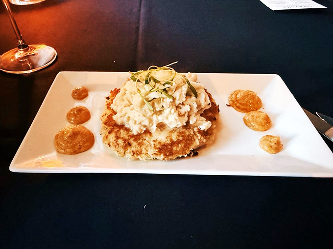 This crab cake isn't playing games—it's a golden-brown disc of oceanic treasure, perched proudly on its plate like it knows exactly how delicious it is.