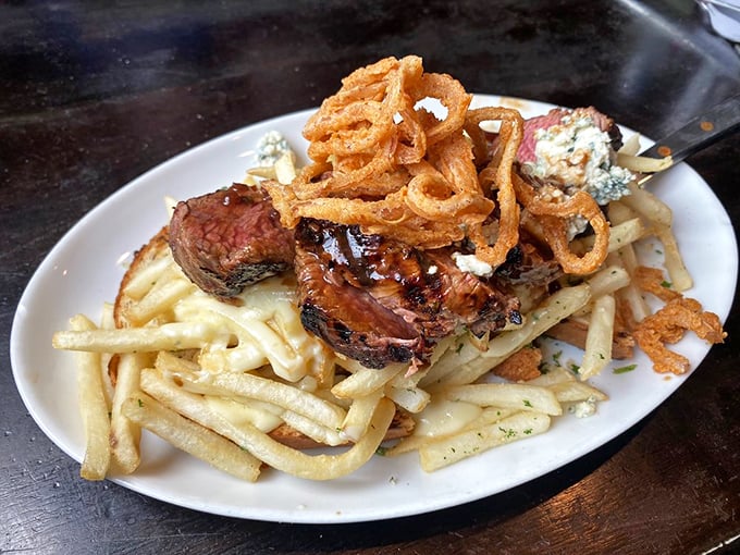 Perfectly seared steak atop golden fries with those crispy onion rings perched like delicious halos &ndash; this plate doesn't just satisfy hunger, it conquers it.