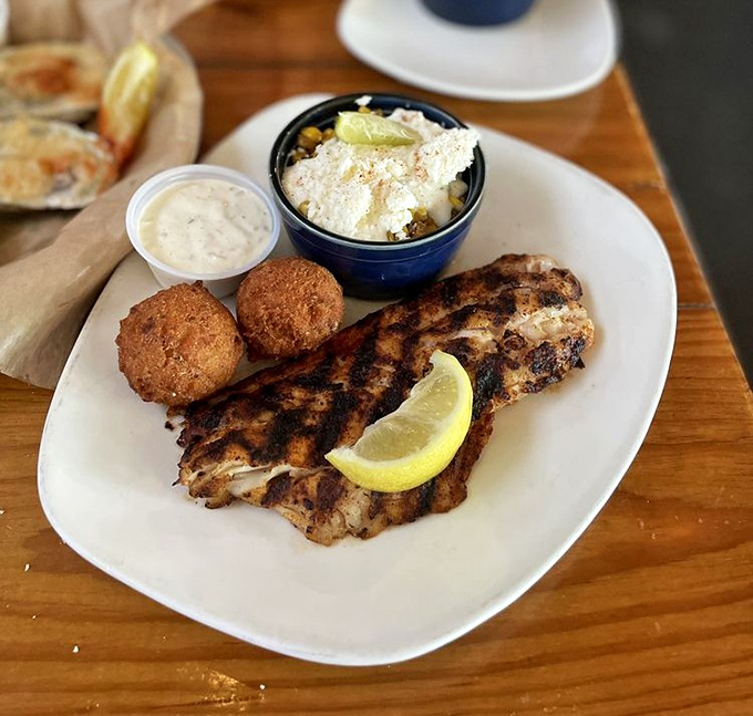 A plate where land meets sea&mdash;grilled fish resting beside hushpuppies and street corn that's dressed up enough for a night on the town.