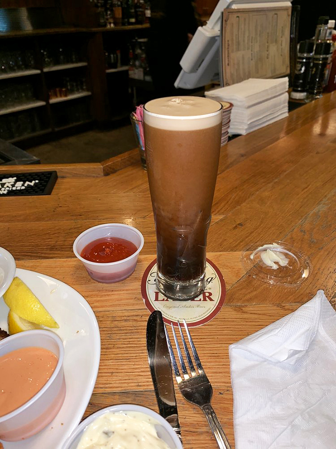 The perfect pint stands tall and proud. A properly poured Guinness with its characteristic creamy head rests on its branded coaster, awaiting the patient drinker.