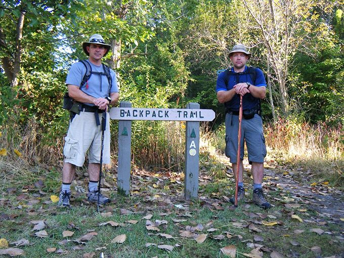 Two hikers pause at the trailhead, contemplating whether their fitness trackers are ready for what the "Backpack Trail" has in store.