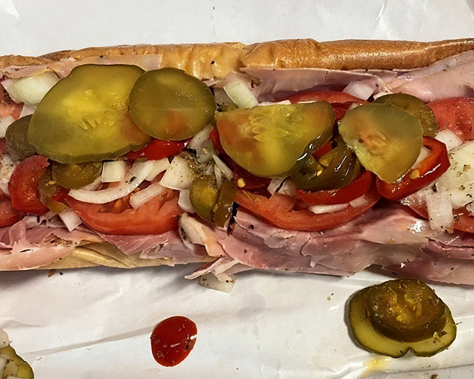 Close-up perfection: paper-thin meats, vibrant tomatoes, and those pickles that somehow tie everything together in a symphony of flavor.