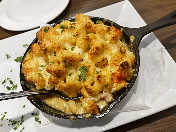Lobster mac and cheese served in a cast iron skillet&mdash;because comfort food deserves to make a dramatic entrance with a golden, bubbling crown.