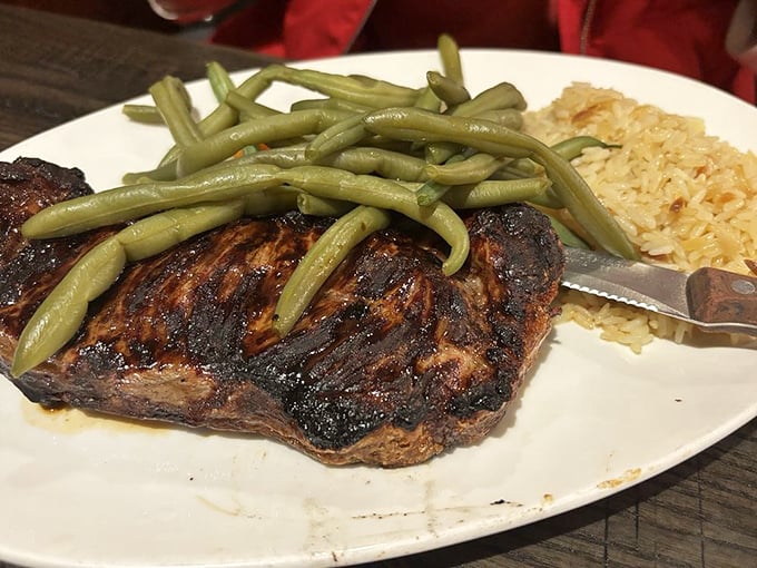 A perfectly grilled steak topped with green beans and rice pilaf&mdash;the kind of straightforward, honest plate that makes you wonder why anyone bothers with fancy restaurants.