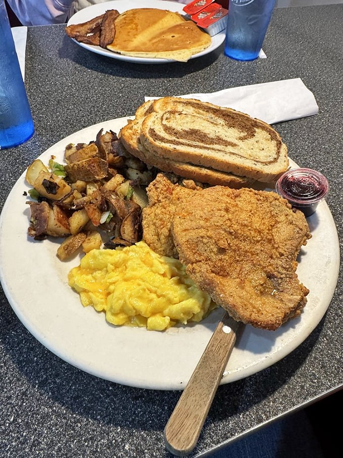 Southern breakfast royalty on a plate: golden hash browns, fluffy eggs, and a pork chop that would make your grandmother proud.
