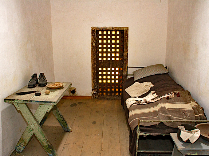 A spartan cell with just the essentials: bed, table, and a door that someone else controlled. Home sweet home? Not exactly.