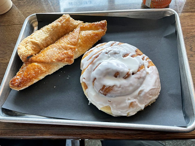 Sweet tooth democracy in action: the cinnamon roll and quesito sharing a tray, proving that breakfast pastries can peacefully coexist despite their delicious differences.