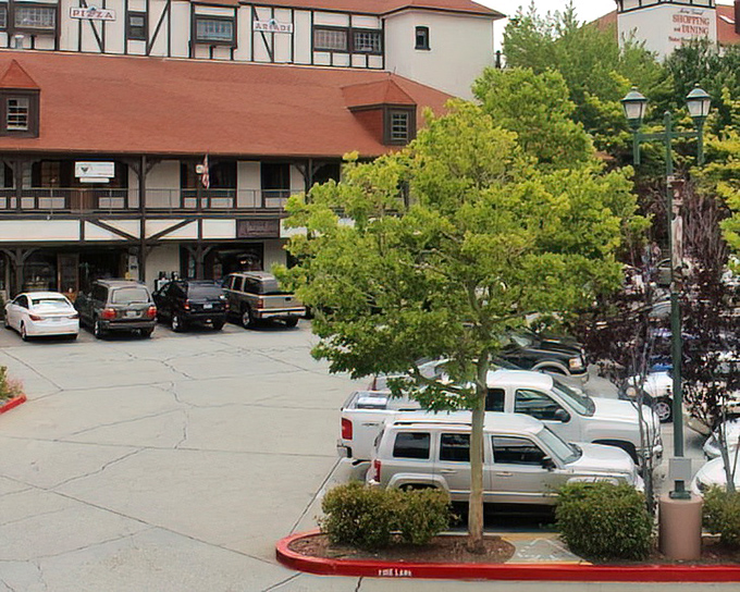 Cars fill the parking area beneath Tudor-style buildings, their drivers likely debating between hiking trails or lakeside lounging for the afternoon.