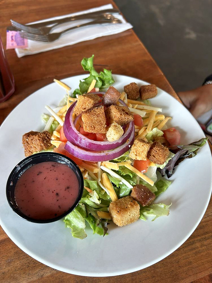 Even the side salad gets star treatment here&mdash;crisp greens, vibrant veggies, and homemade croutons that refuse to be mere supporting actors.
