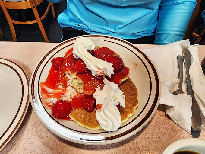 Strawberry pancakes crowned with whipped cream clouds. Dessert masquerading as breakfast, and nobody's complaining about the deception.