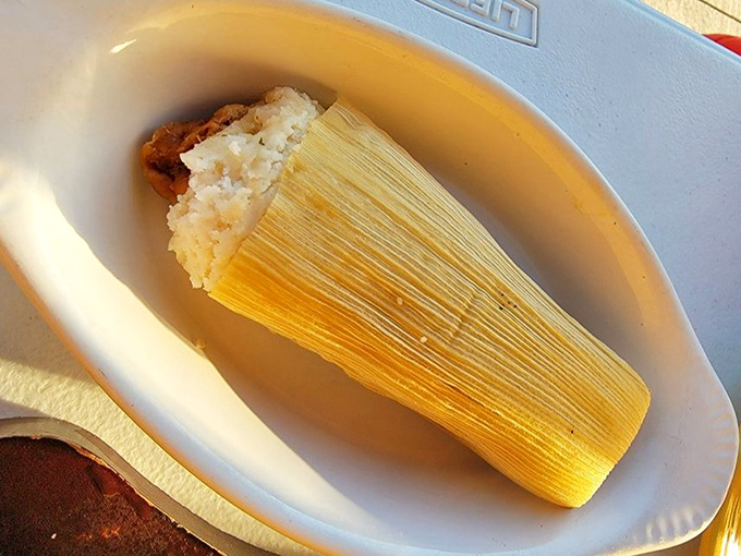 This tamale isn't just unwrapped—it's revealing its steamy corn masa secrets after a long, cozy slumber in its corn husk blanket.