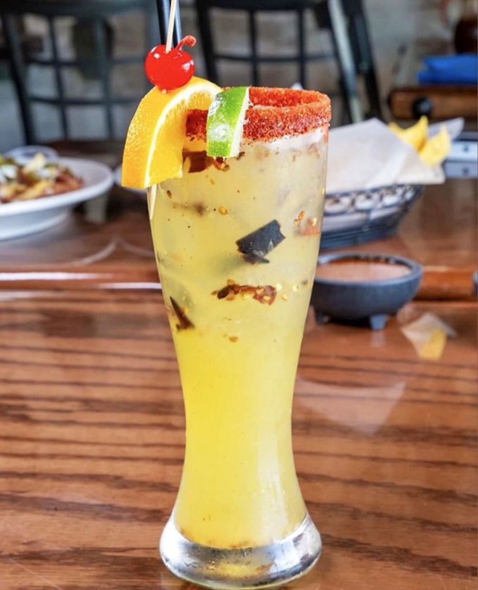 A tropical margarita that looks like liquid sunshine, rimmed with chili salt and garnished with citrus – vacation in a glass, no passport required.