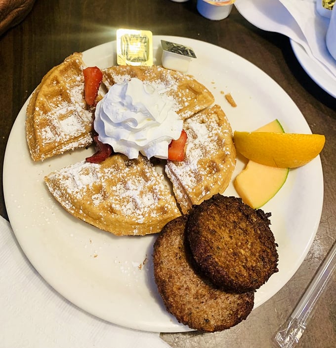 Golden Belgian waffle perfection with strawberries and whipped cream, paired with sausage patties for that sweet-savory balance we all crave.