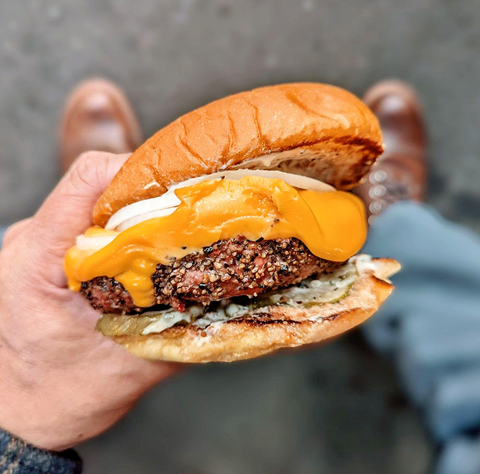 This isn't just a burger—it's a structural engineering marvel with melty cheese cascading down a blackened patty like lava from a delicious volcano.