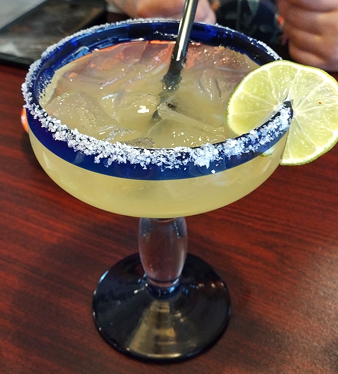 The margarita's salt rim isn't just decoration&mdash;it's the perfect prelude to that sweet-tart symphony waiting inside the blue-rimmed glass.