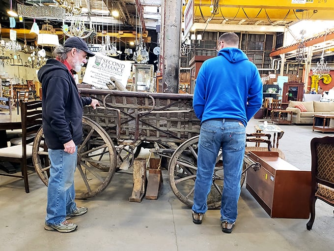 Two treasure hunters contemplating what appears to be a vintage wagon&mdash;proof that at Second Chance, "impulse buy" can mean anything from a doorknob to a horse-drawn carriage.