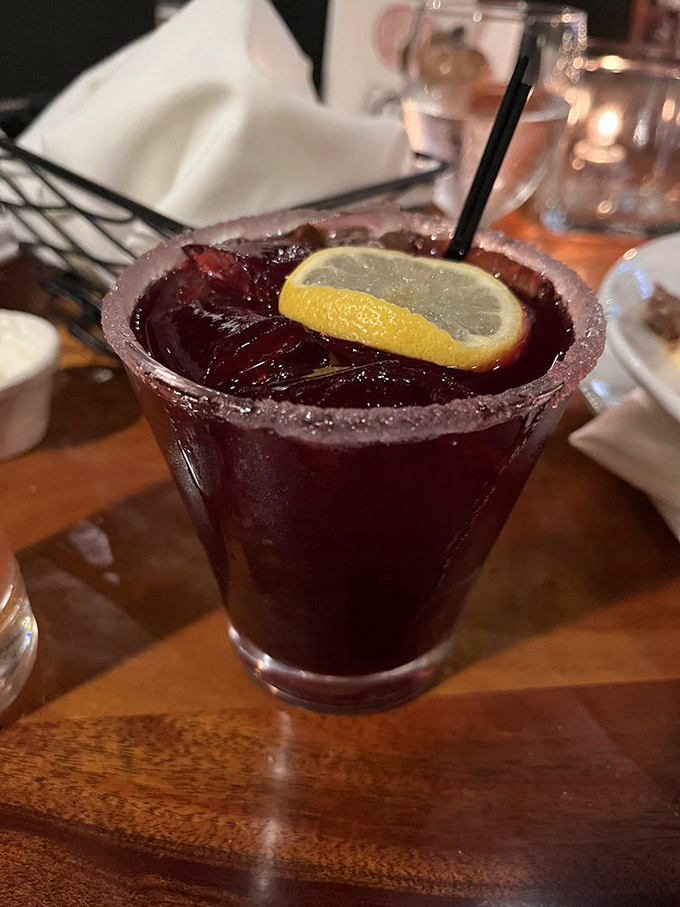This isn't just a cocktail—it's a ruby-red liquid vacation with a sugar-rimmed passport and a lemon slice that's along for the ride.