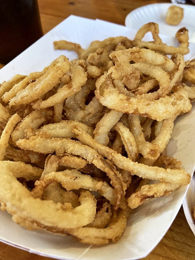 Onion rings stacked like delicious golden halos. Not those sad, uniform frozen circles—these are the hand-breaded beauties that dreams are made of.