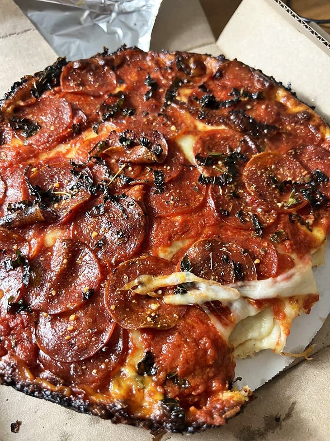 The holy trinity of pizza perfection: pepperoni crisped at the edges, that signature blackened cheese border, and enough sauce to make an Italian grandmother weep.