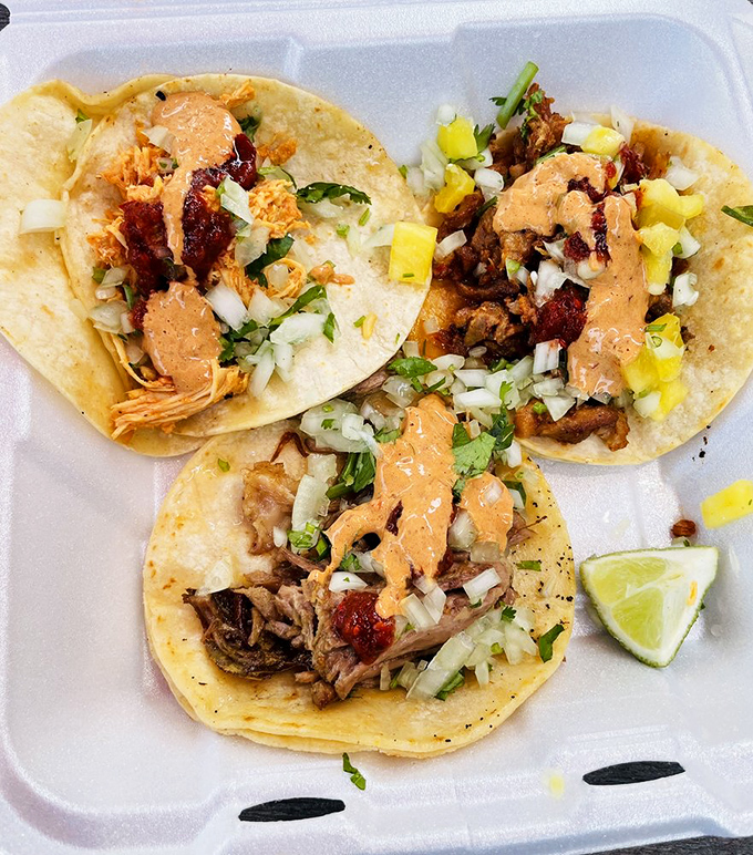 Taco perfection in triplicate. These street-style beauties feature the holy trinity of Mexican toppings: cilantro, onion, and a splash of creamy sauce.