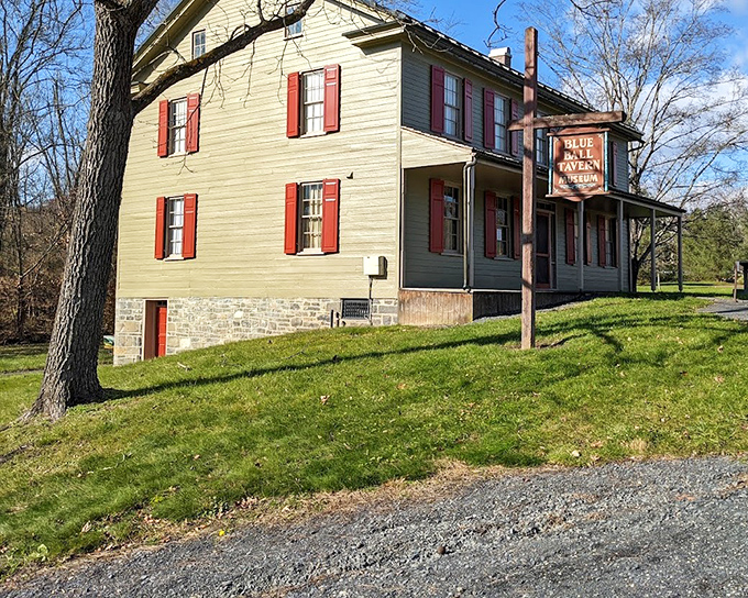 The Blue Ball Tavern stands with dignified charm, its yellow clapboard and red shutters recalling an era of stagecoach travelers and fireside tales.