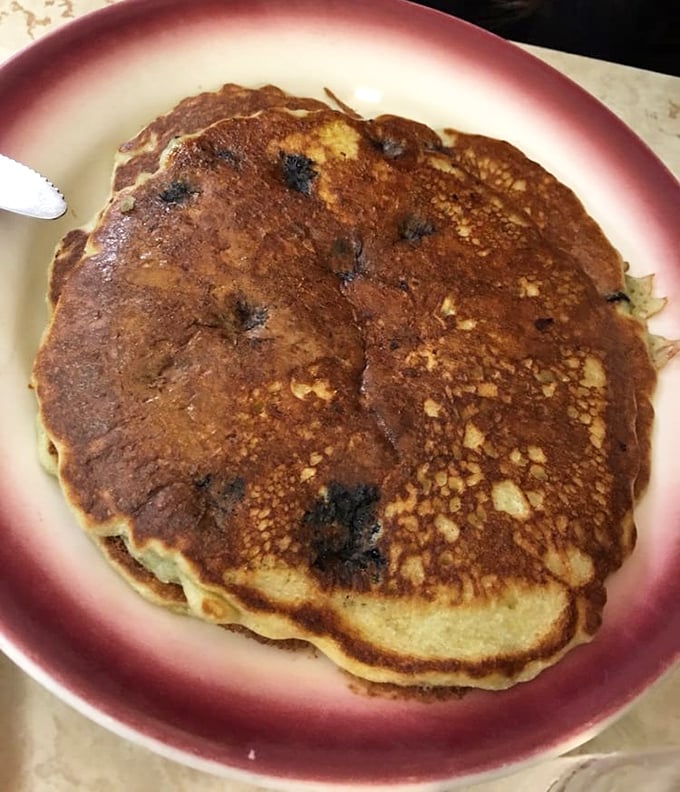 A blueberry pancake the size of a frisbee, with those perfectly imperfect bursts of fruit that remind you someone actually made this by hand.