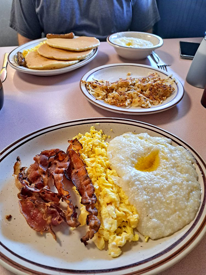 The breakfast trinity: perfectly crisp bacon, fluffy scrambled eggs, and grits that would make any Southerner nod in approval.