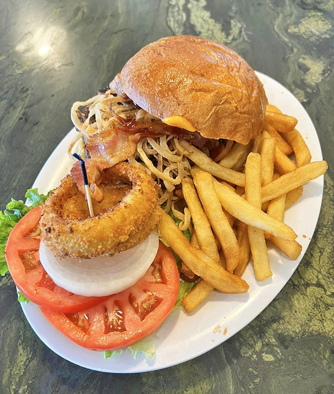A burger that requires a game plan before the first bite, with an onion ring sentinel standing guard and fries that demand equal attention. 