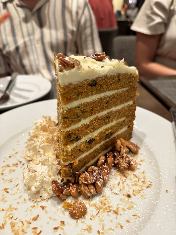 Carrot cake reimagined as a towering architectural achievement. Those candied pecans aren't just garnish&mdash;they're the crown jewels.