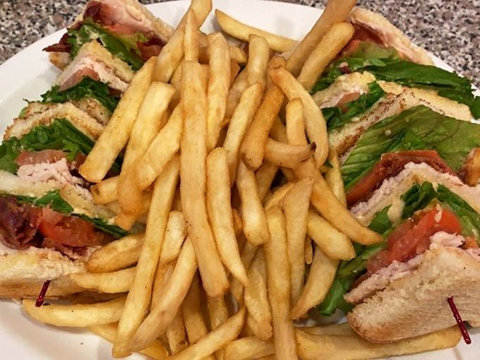 The club sandwich stands tall and proud, layers of fresh ingredients stacked between toast like a skyscraper of flavor, with crispy fries standing guard. 