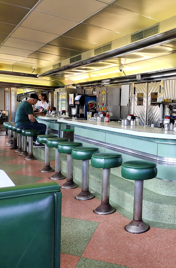 The green counter stools have witnessed decades of first dates, family meals, and solo diners finding comfort in both food and community.