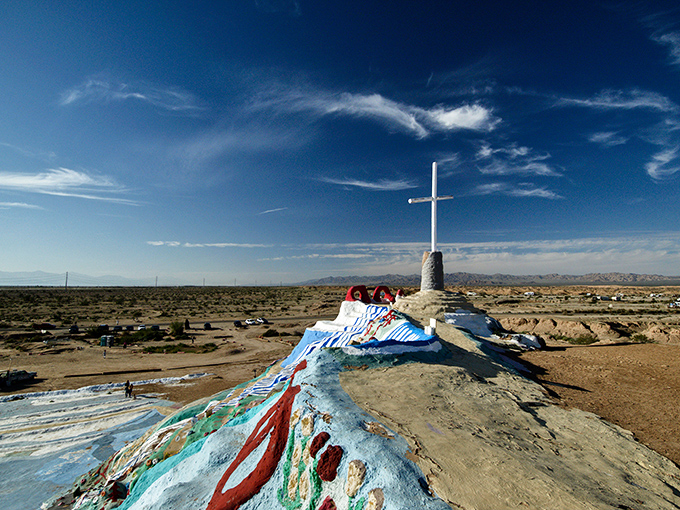 The cross stands tall against an impossibly blue sky, marking the summit of this improbable desert masterpiece.