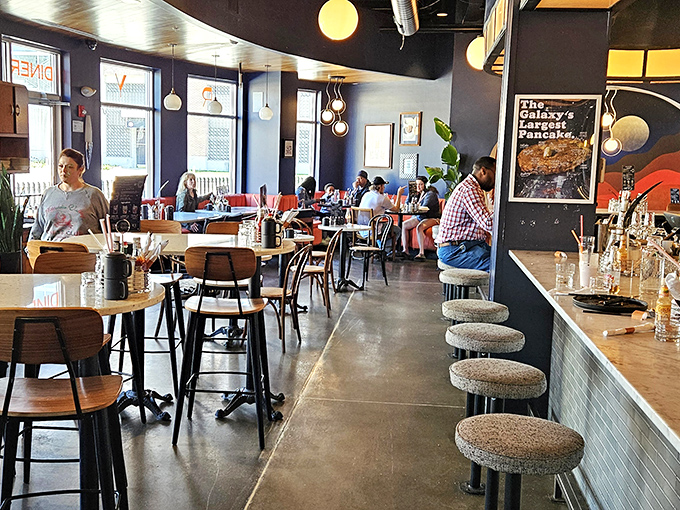The dining room buzzes with conversation and anticipation, where modern design meets nostalgic comfort in a space that feels simultaneously familiar and fresh.