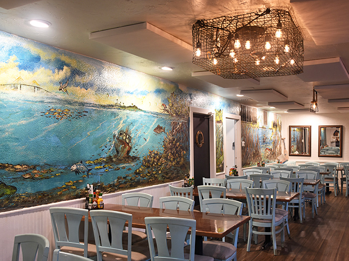 The coastal mural transforms an ordinary dining room into an underwater fantasy, like eating inside a postcard from Old Florida.